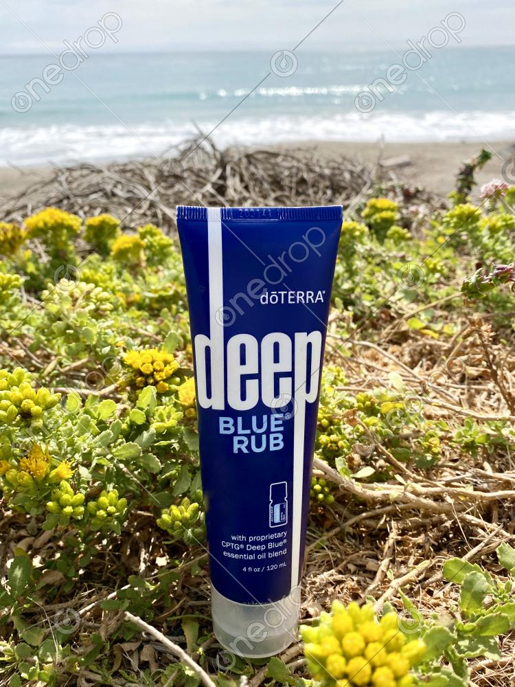 dōTERRA Deep Blue framed by flowers and the ocean by Robert Griego